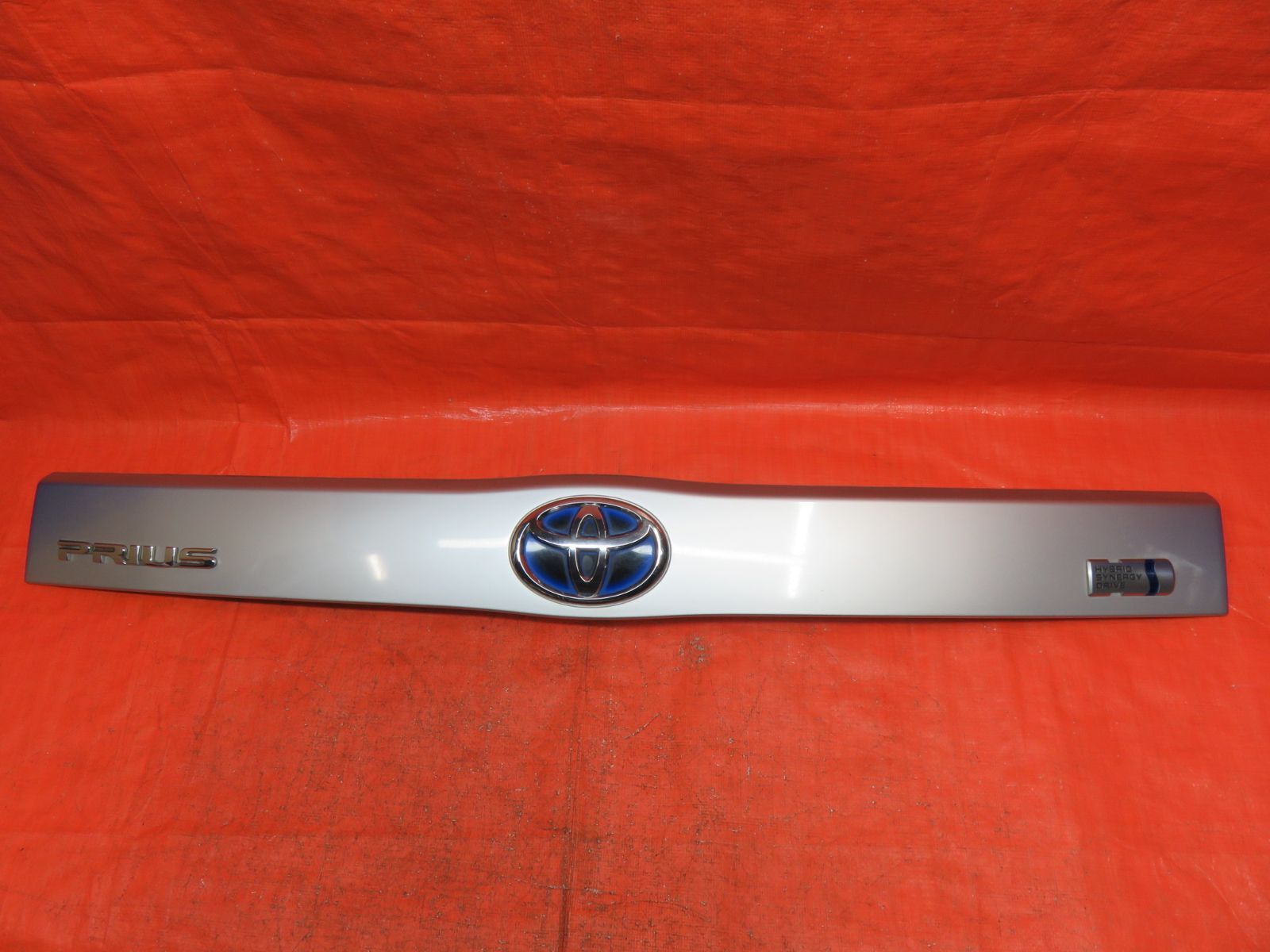 LA2730* プリウス DAA-ZVW30 リアガーニッシュ/フィニッシャーパネル/エンブレム オーナメント/純正 76801-47070 ...